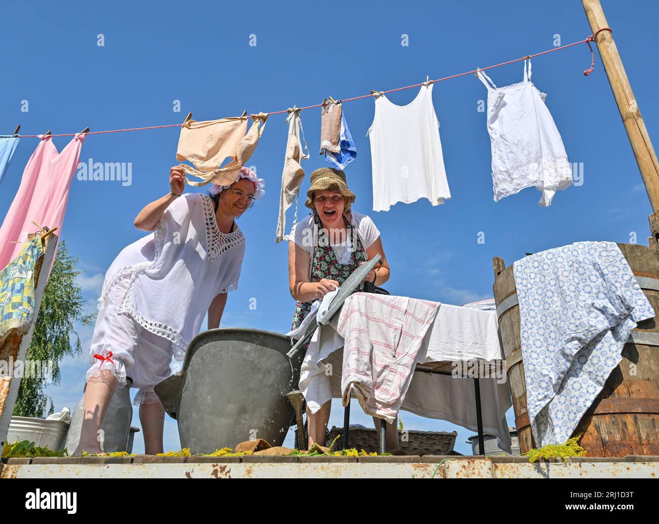 Burg, Germany. 20th Aug, 2023. Two women show how laundry was washed ...