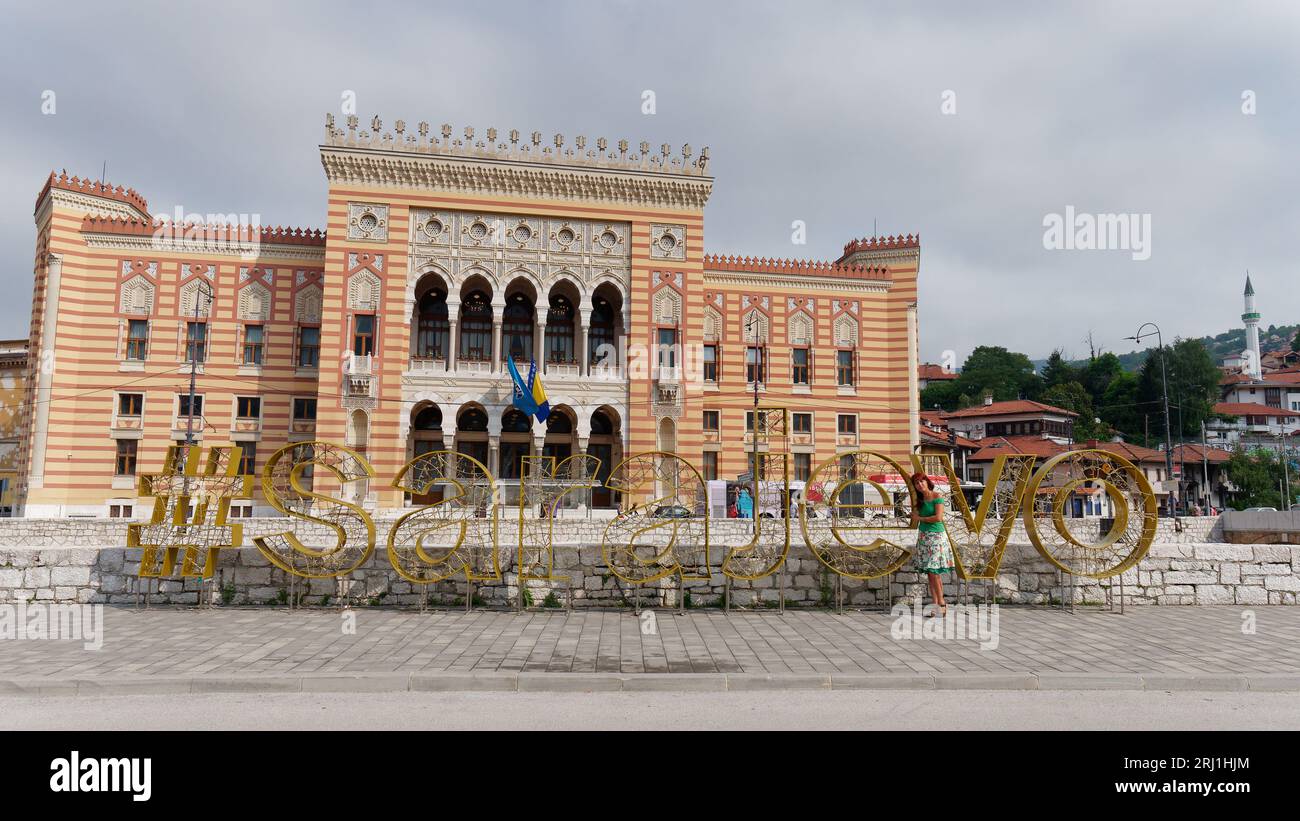 Tourist stands by the Sarajevo Sign in front of City Hall in the city ...