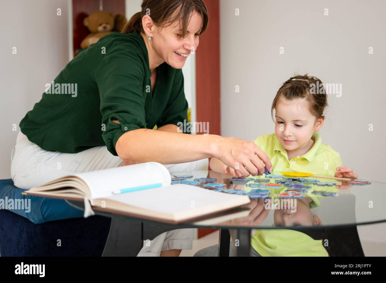 Female child psychologist working with a little girl in a bright office ...