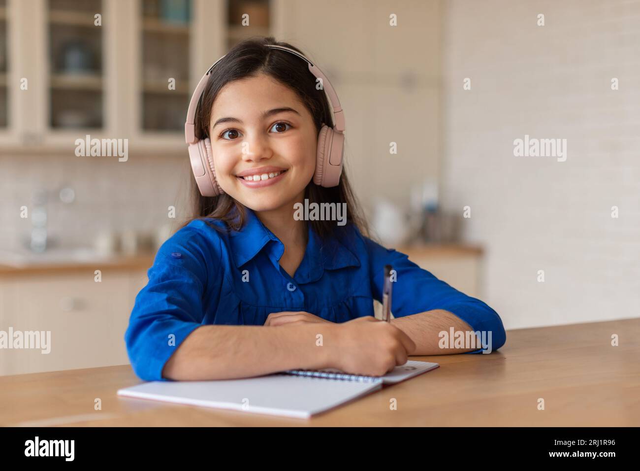 Happy School Girl Learning, Writing in Notebook Wearing Earphones ...