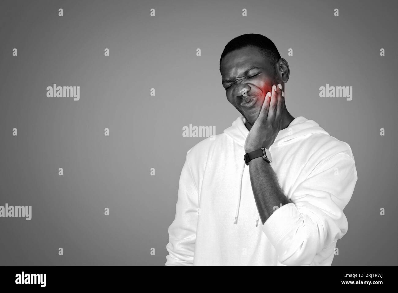 Sad Millennial African American Guy In Hoodie Presses Hand To Cheek