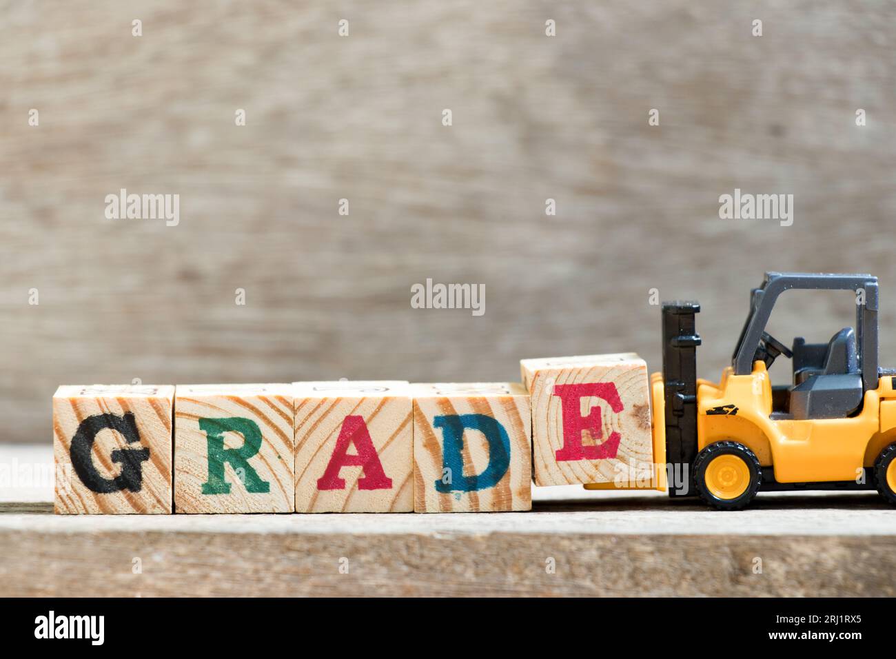 Toy forklift hold letter block in word grade on wood background Stock ...