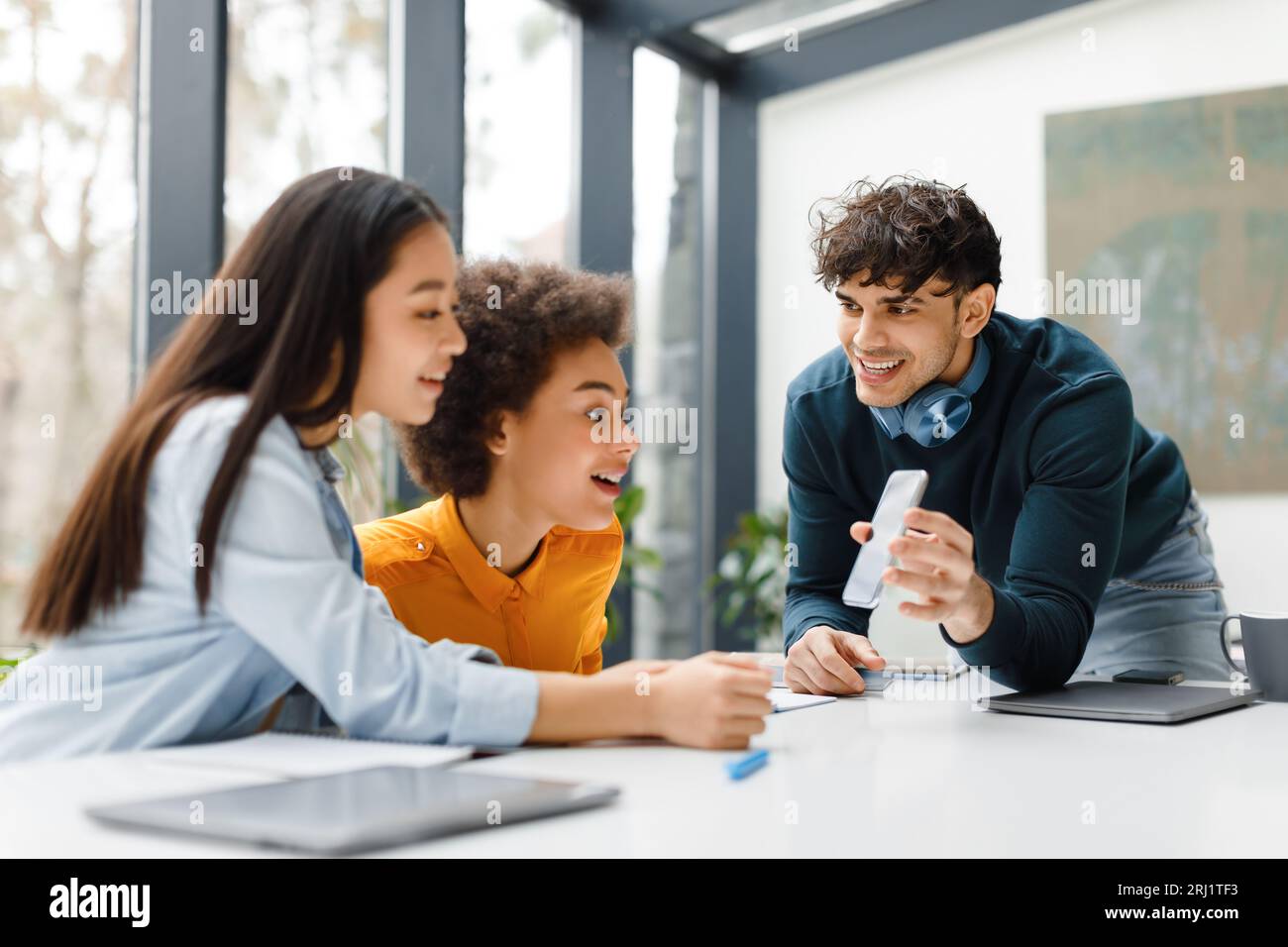 Happy european guy showing cellphone with blank screen to diverse ...