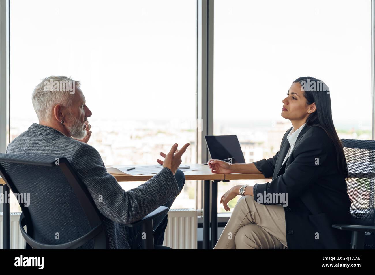 Two business colleagues talking in meeting room during work on project ...