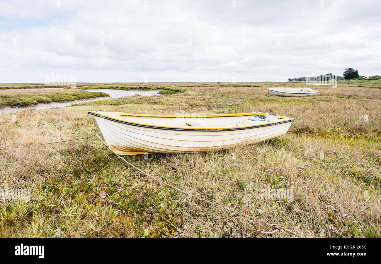 Three small boats tied up on the marshes at Brancaster Staithe ...