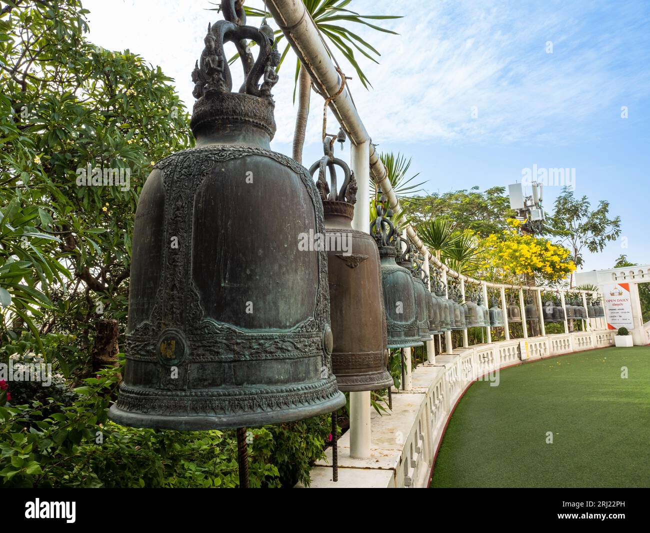 Bronze bells form a graceful curve amidst green trees and a vivid blue ...