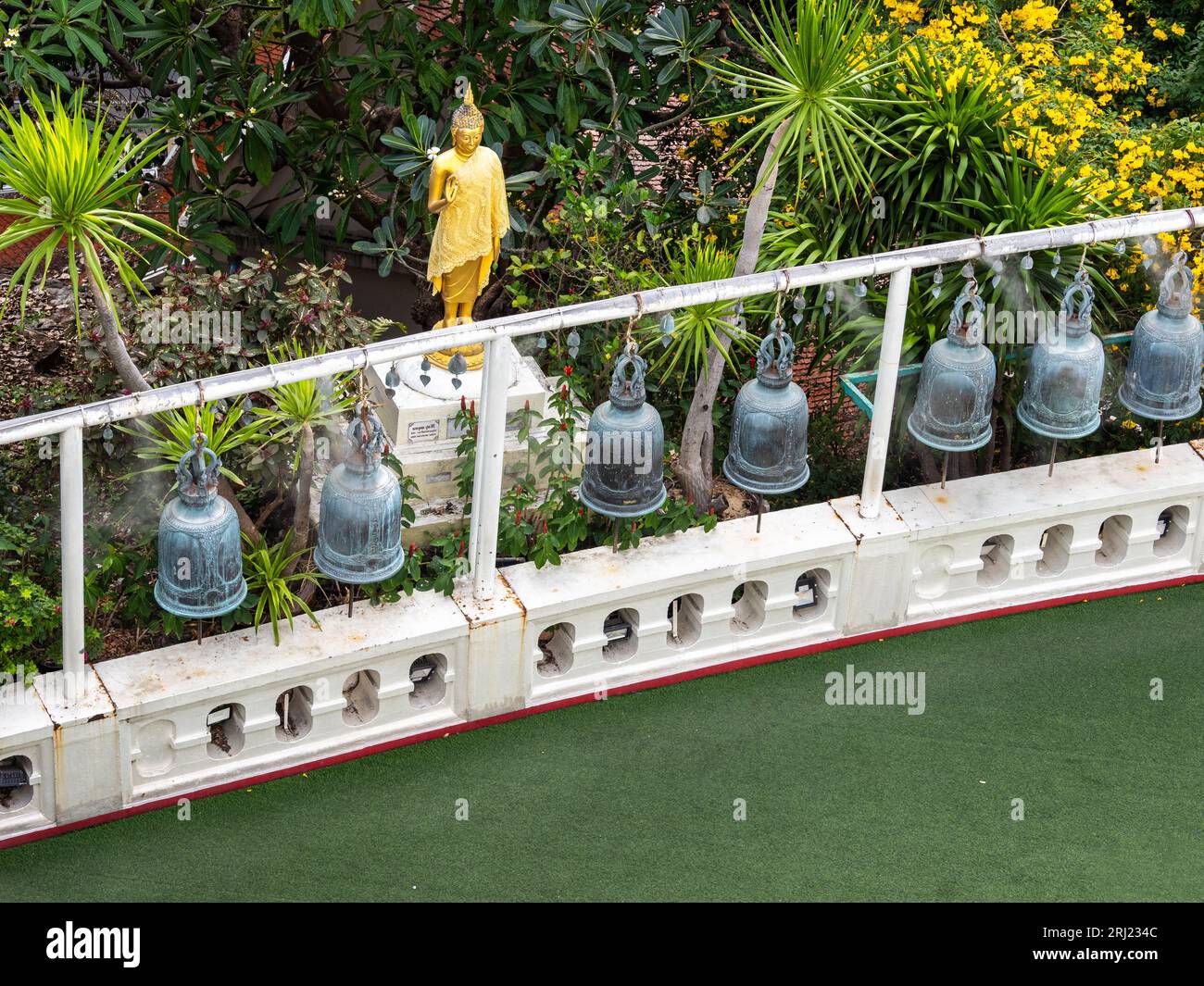 Viewed from above, a row of bells stretches before a golden Buddha ...