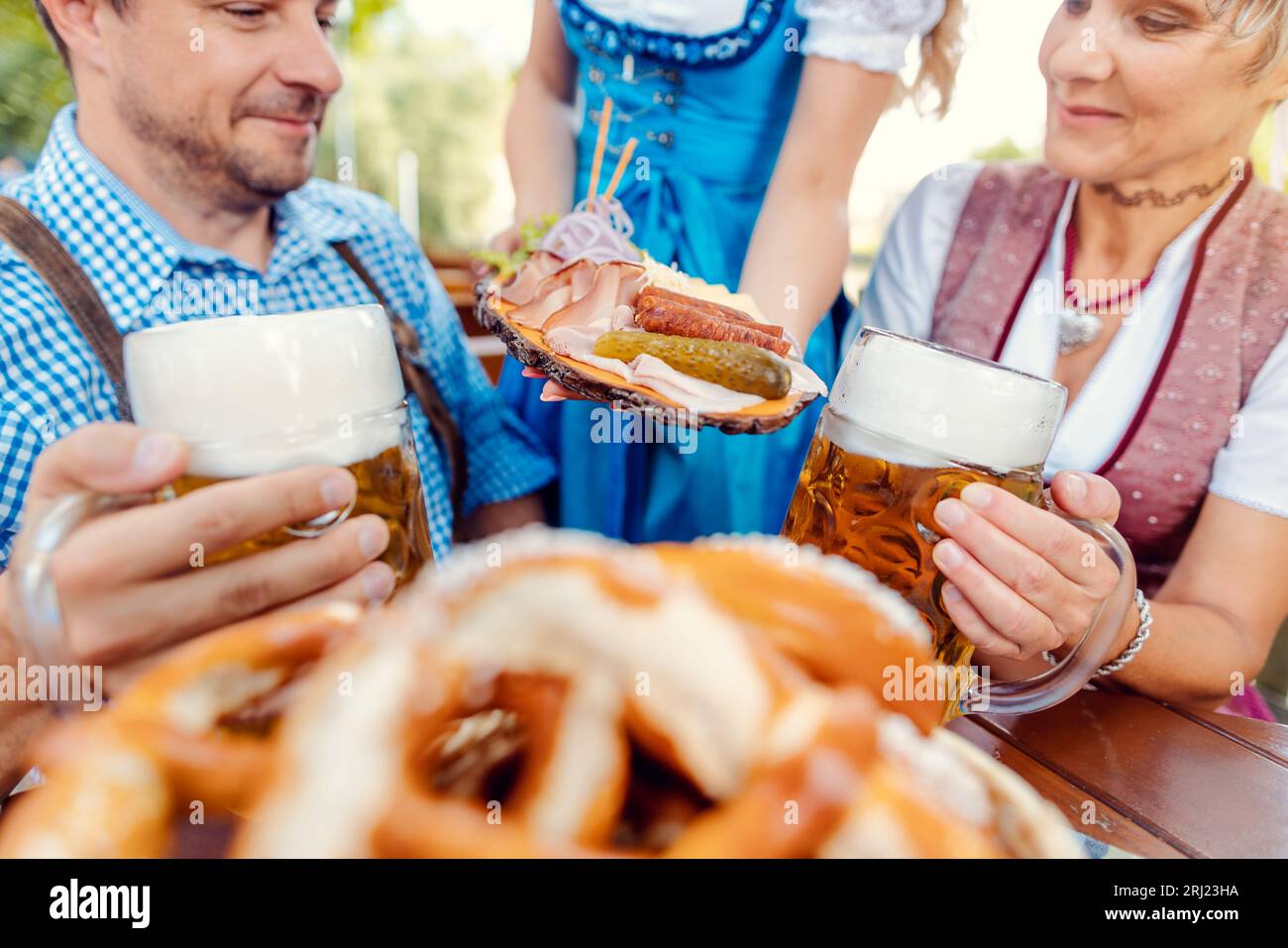 Server bringing food to couple in beer garden Stock Photo - Alamy