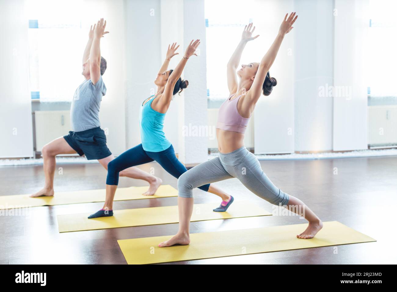 Three sporty people in the warrior I pose Stock Photo - Alamy