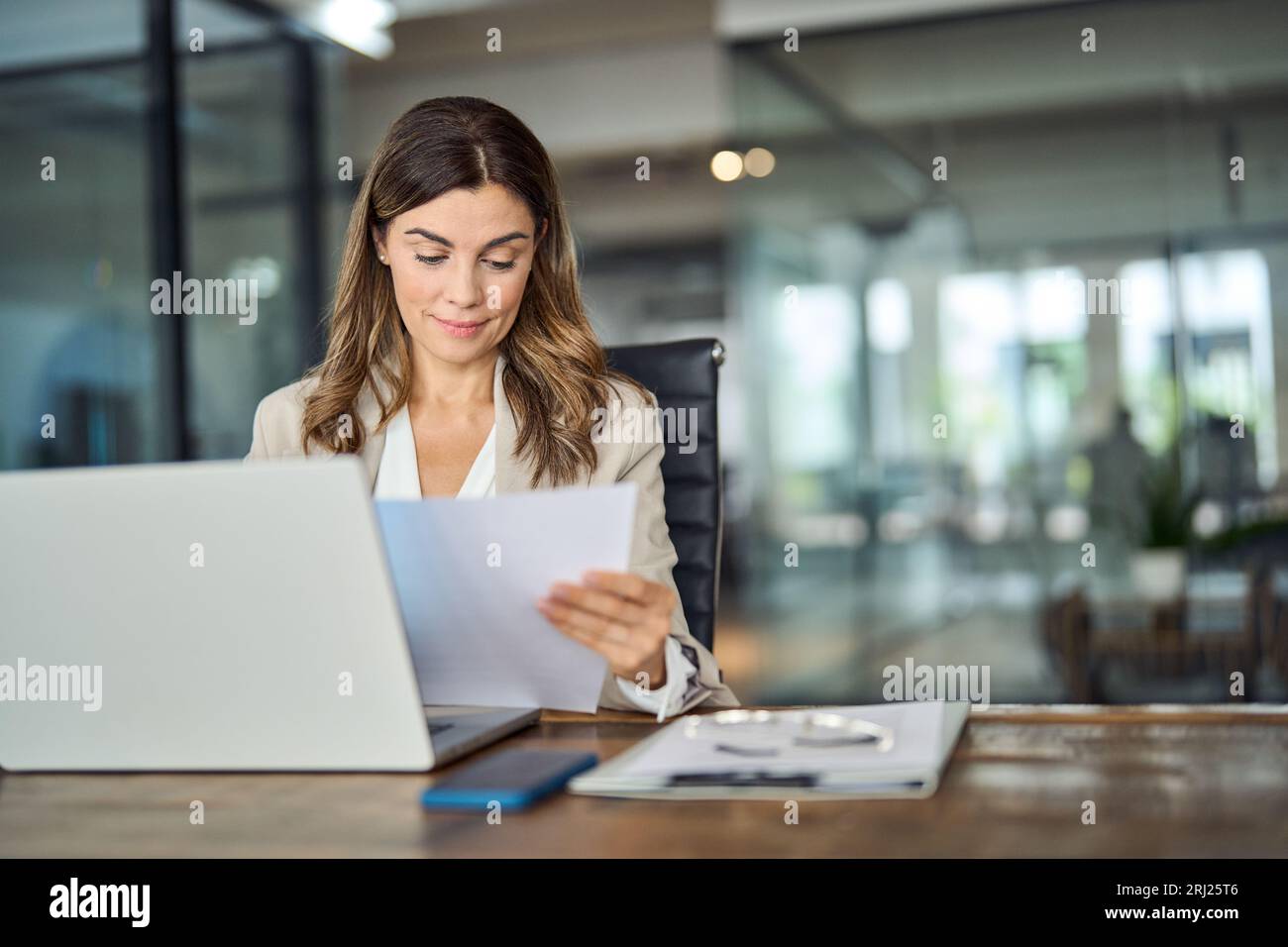 Busy mid aged business woman working in office with laptop and ...