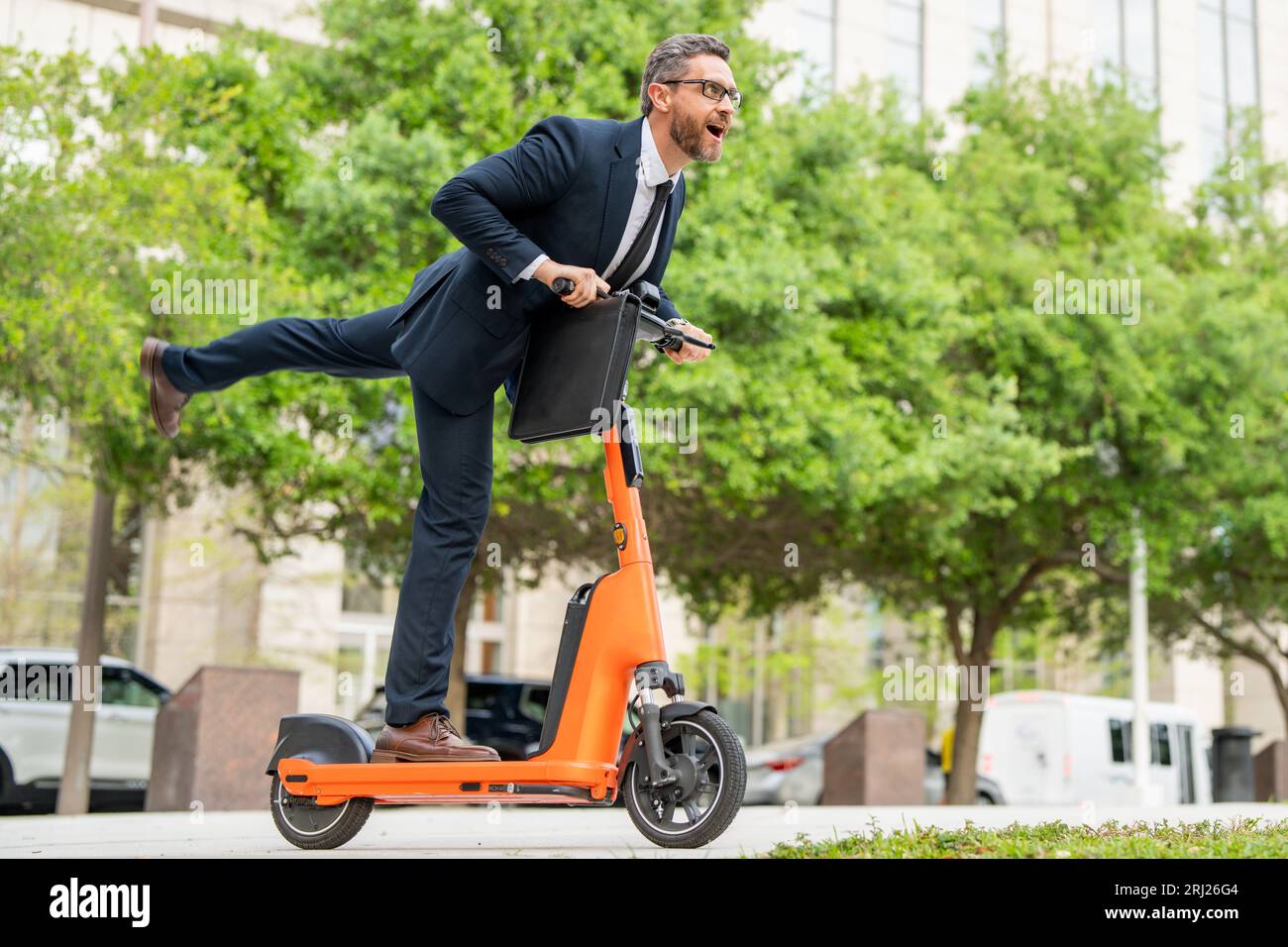 Funny excited business man in a suit riding an scooter on a business ...