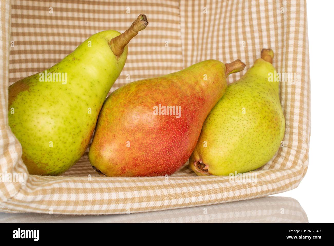 Three organic juicy pears in a basket, close-up, on a white background ...