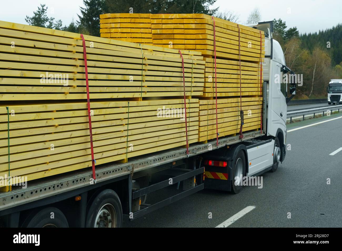 A truck transports lumber - boards on a motorway on a semi-trailer. In ...