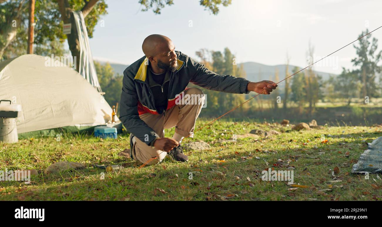 Camping, tent in ground and black man setup in nature for shelter on ...
