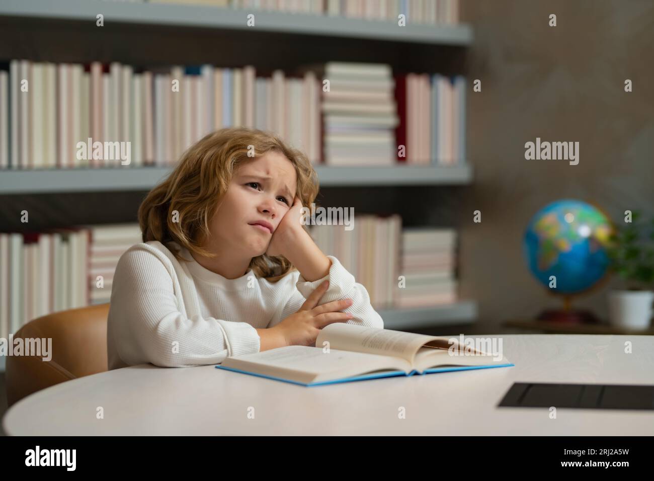 Tired school boy, bored pupil at school. Pupil reading books in a ...