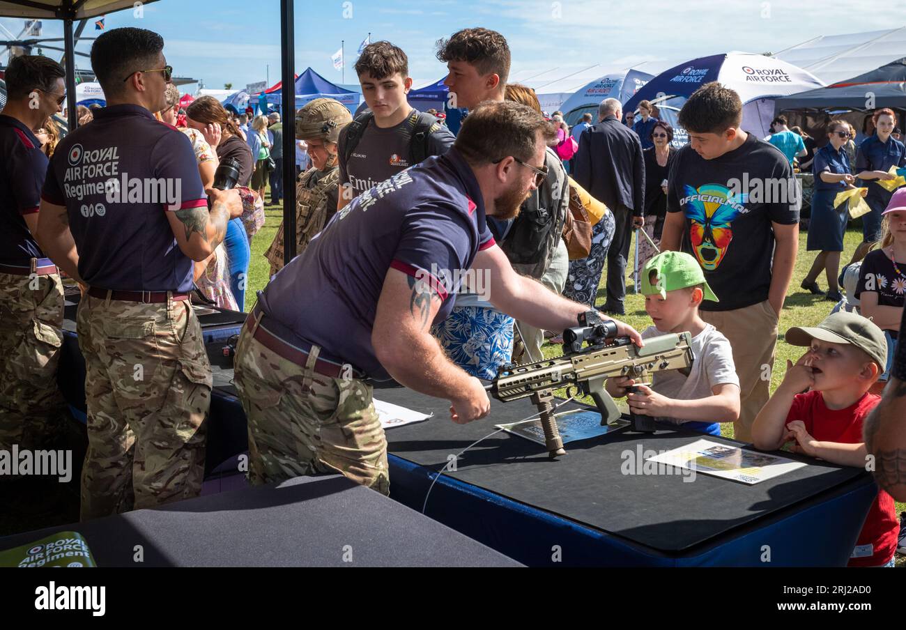 A young boy is shown a SA80 assault military rifle by a soldier from ...