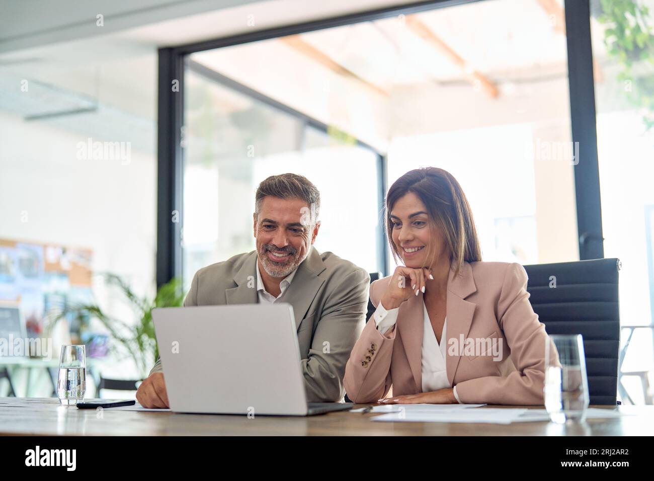 Two happy professional business executives working in office looking at laptop Stock Photo - Alamy