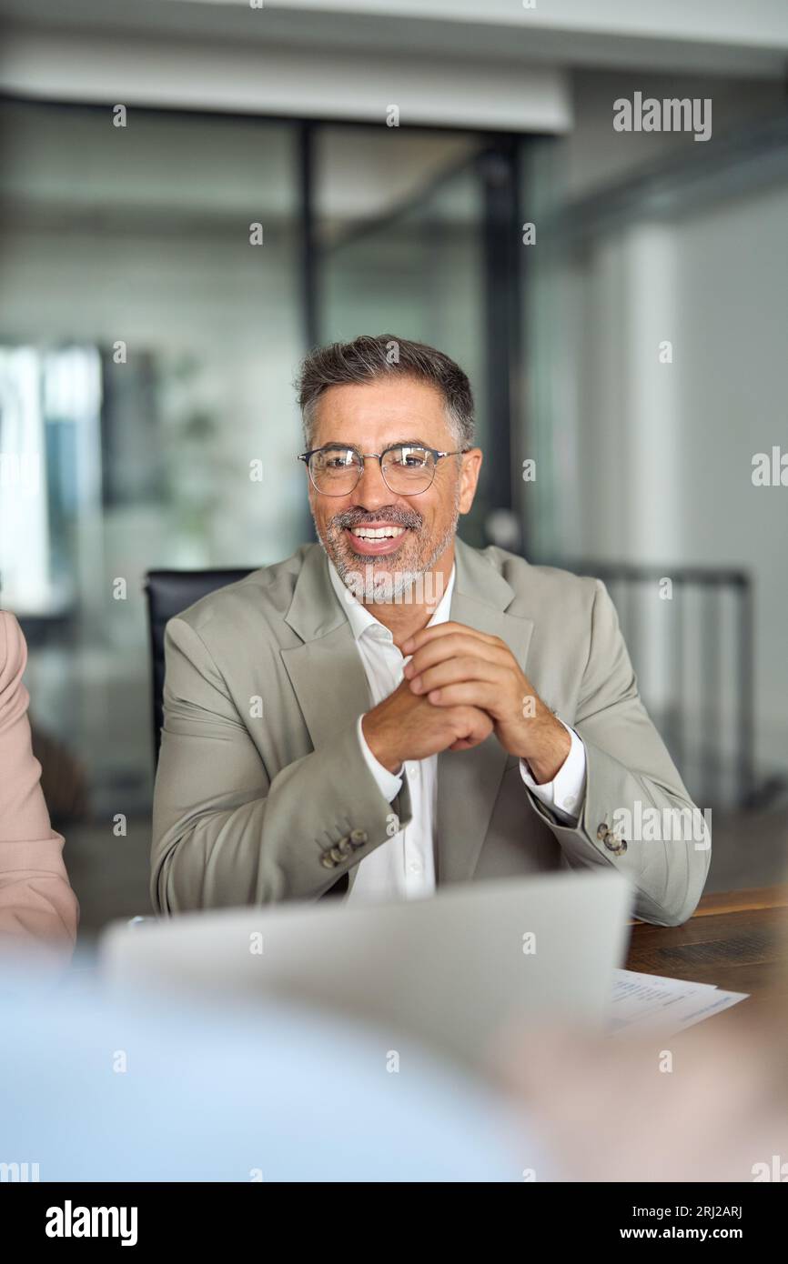 Smiling Latin business man manager working at team office meeting table ...