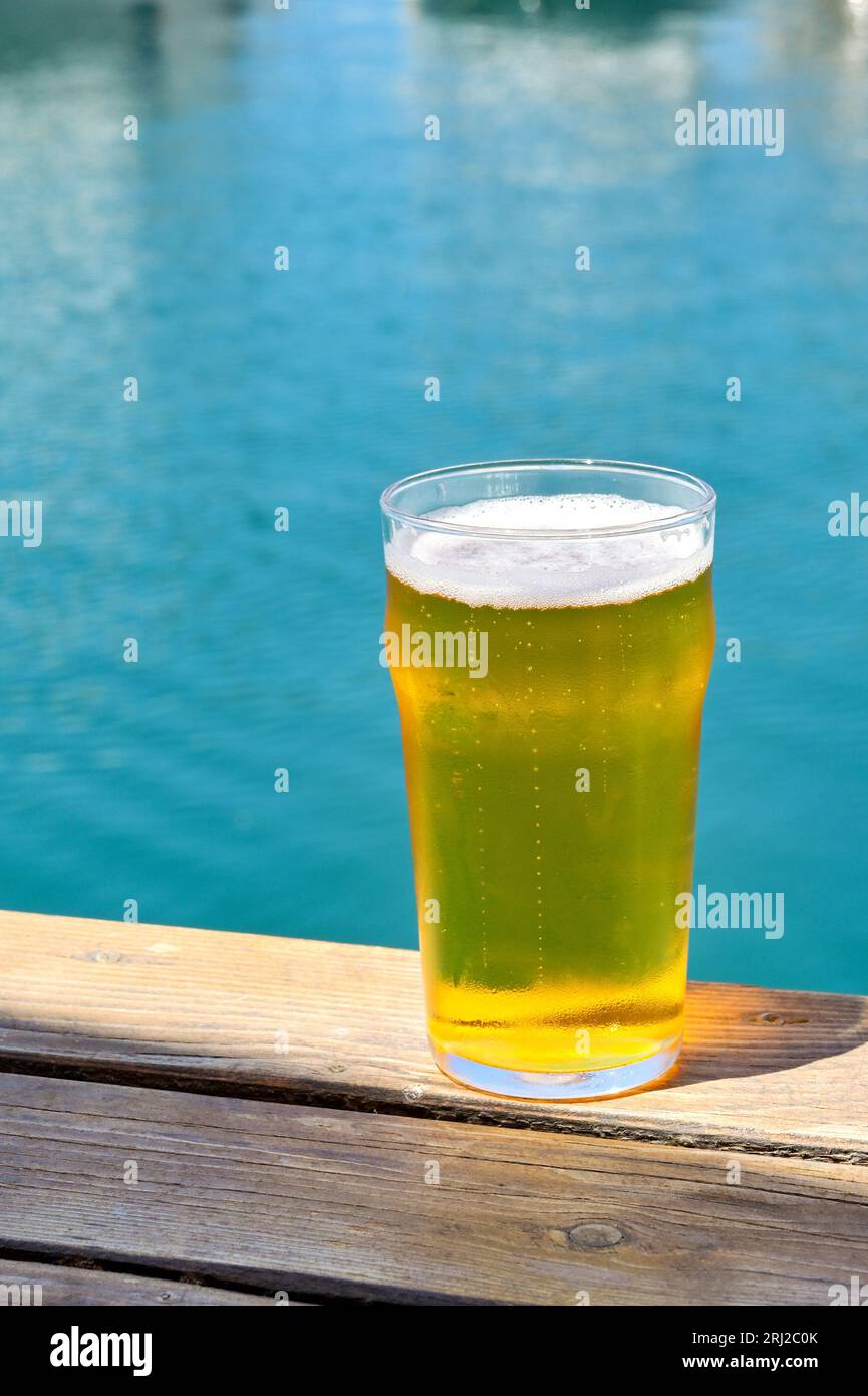 Pint of golden colour lager beer in a waterfront bar overlooking a ...