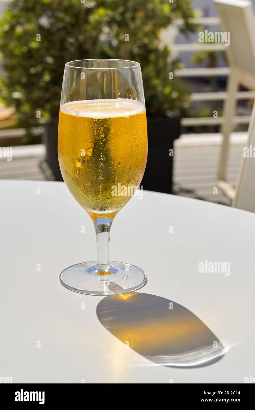Glass of chillded golden colour lager beer on a table on the outdoor ...