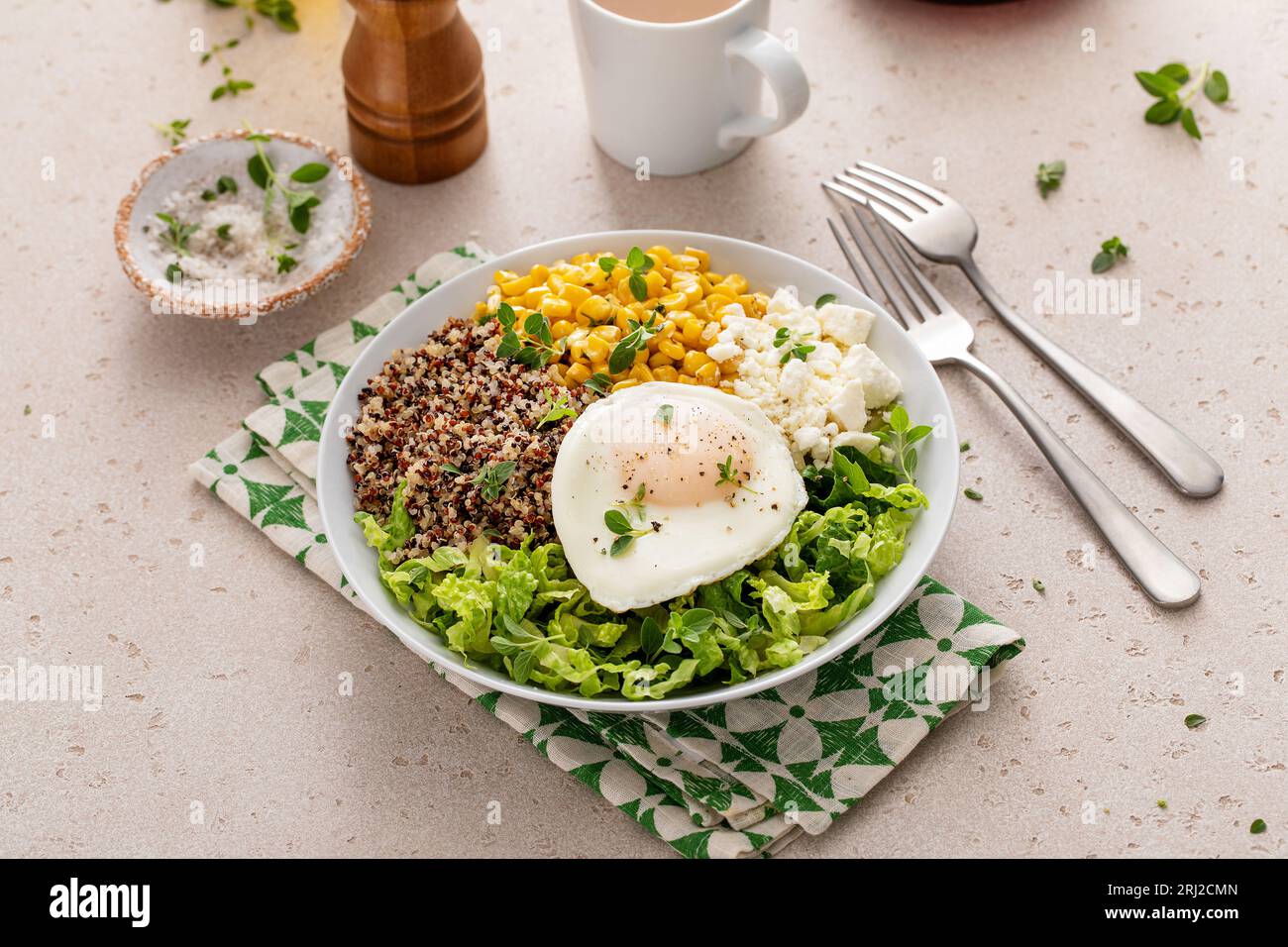 Breakfast bowl with quinoa, herbed corn, feta cheese and fried egg on ...