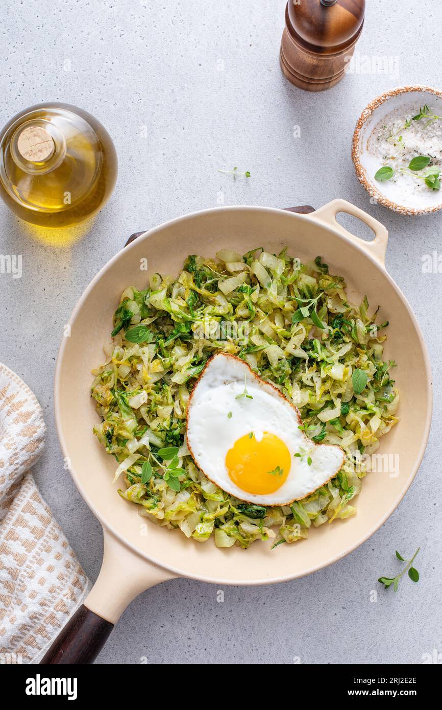 Sauteed cabbage topped with fried egg in a cast iron pan, healthy ...