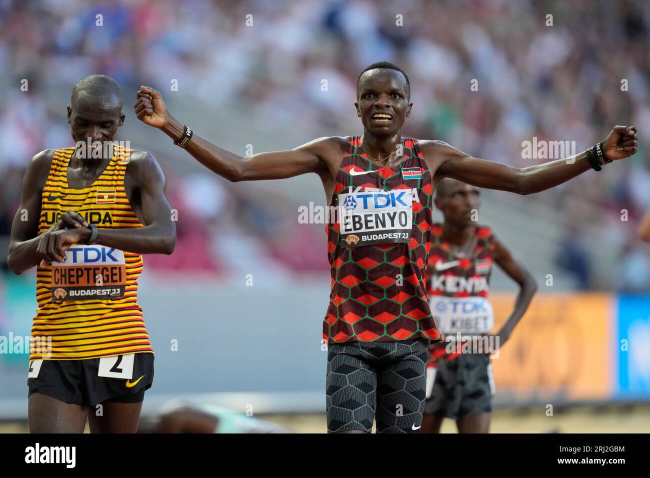Joshua Cheptegei, of Uganda, left, checked his time as he celebrates ...