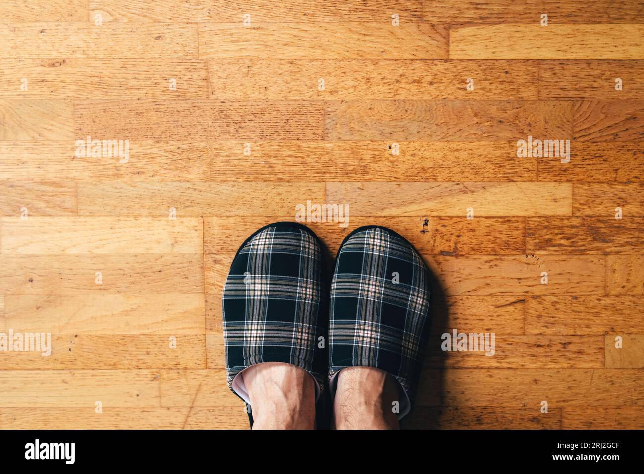 Top view of male feet wearing home slippers and standing on hardwood ...