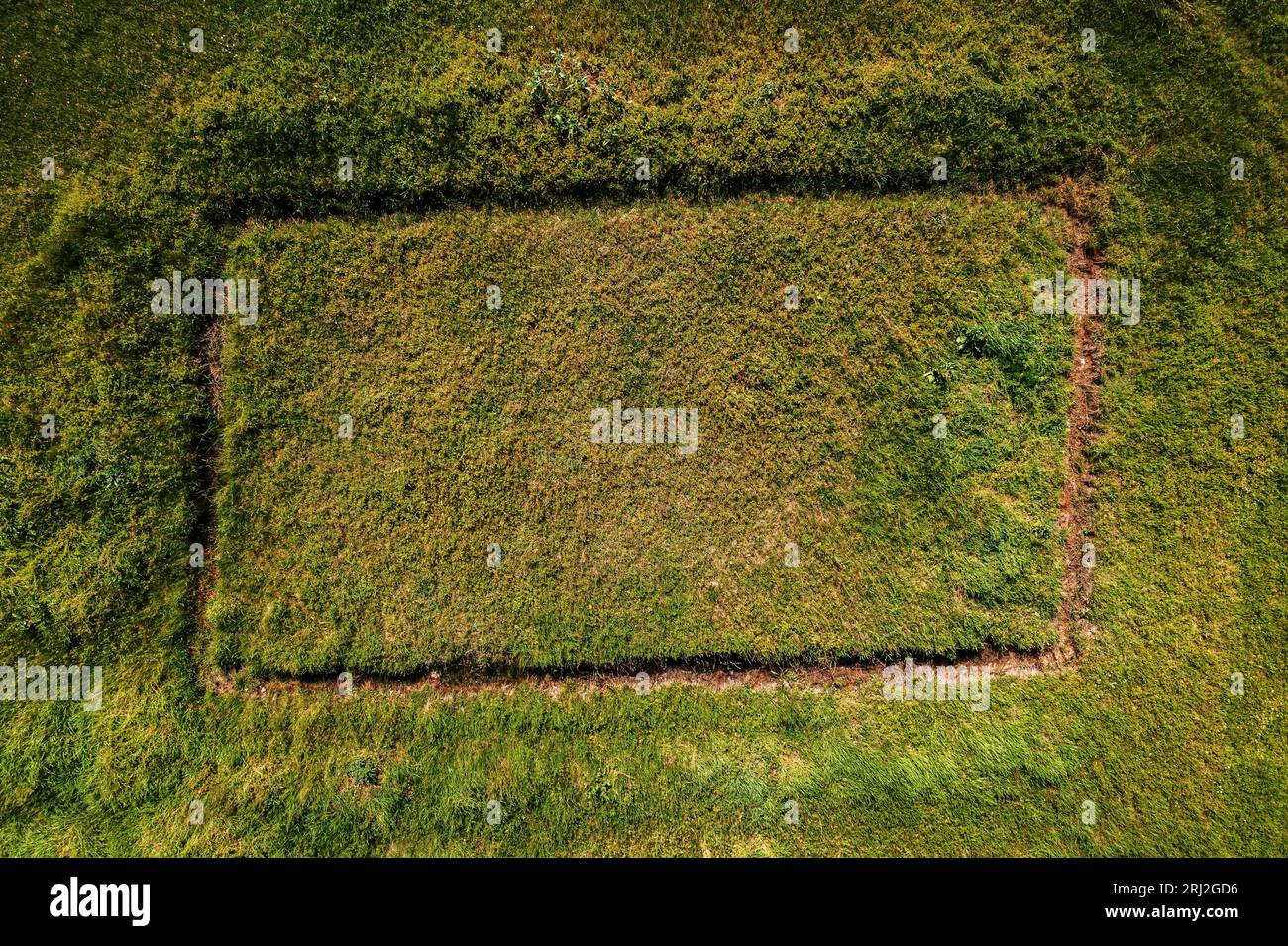 Aerial shot of unfinished house foundation in grass field from drone ...