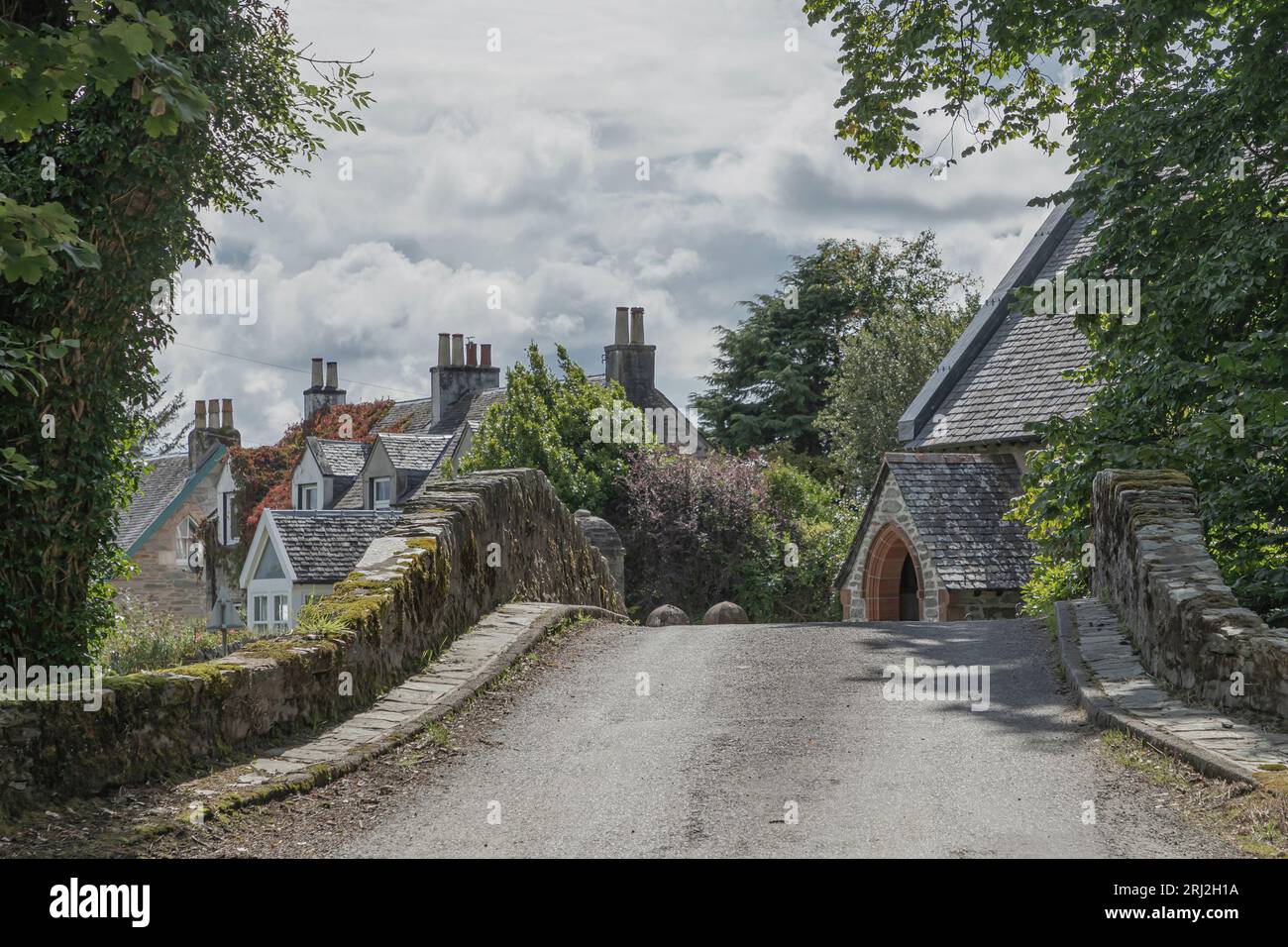 Road over an old stone bridge with houses on the other side in Summer ...
