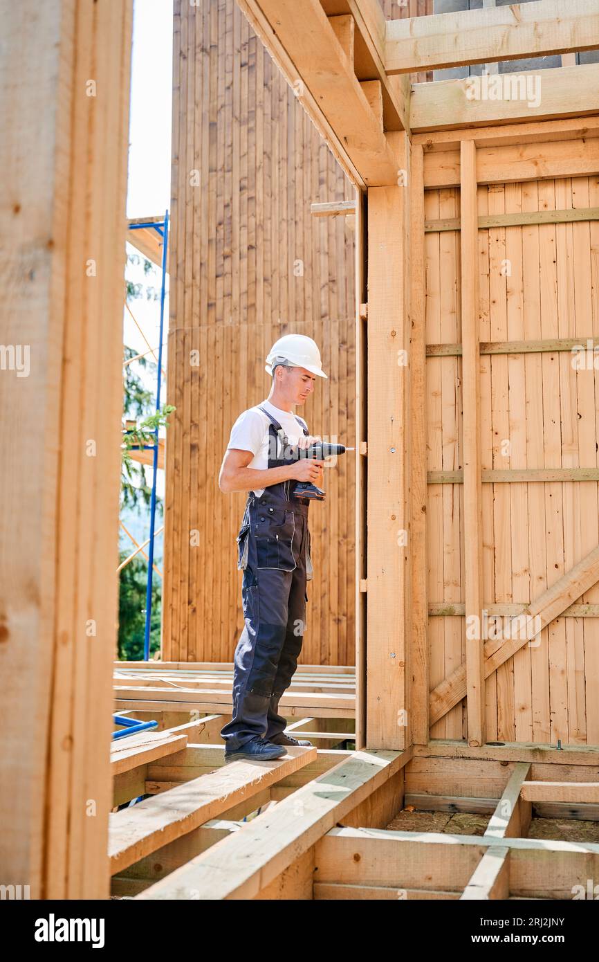 Carpenter constructing wooden framed house. Man worker cladding facade ...