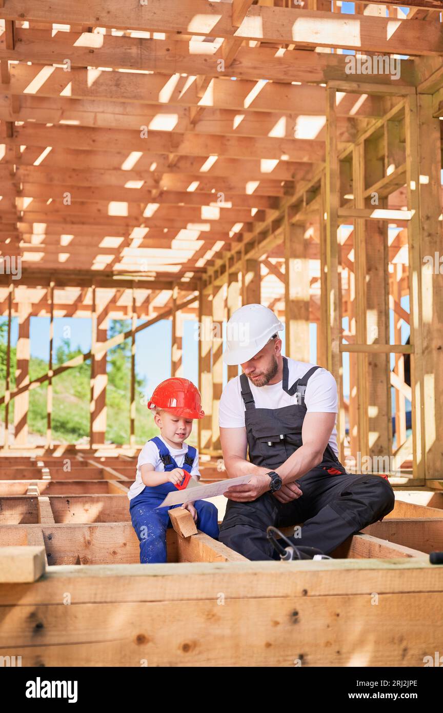 Father with toddler son constructing wooden frame house. Male builder ...
