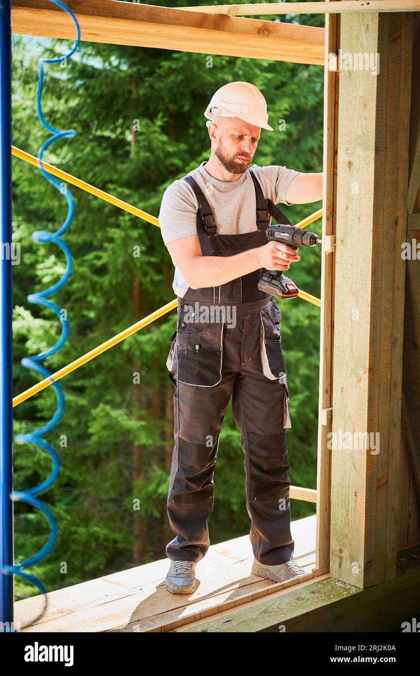 Carpenter constructing wooden framed house. Bearded man worker cladding ...