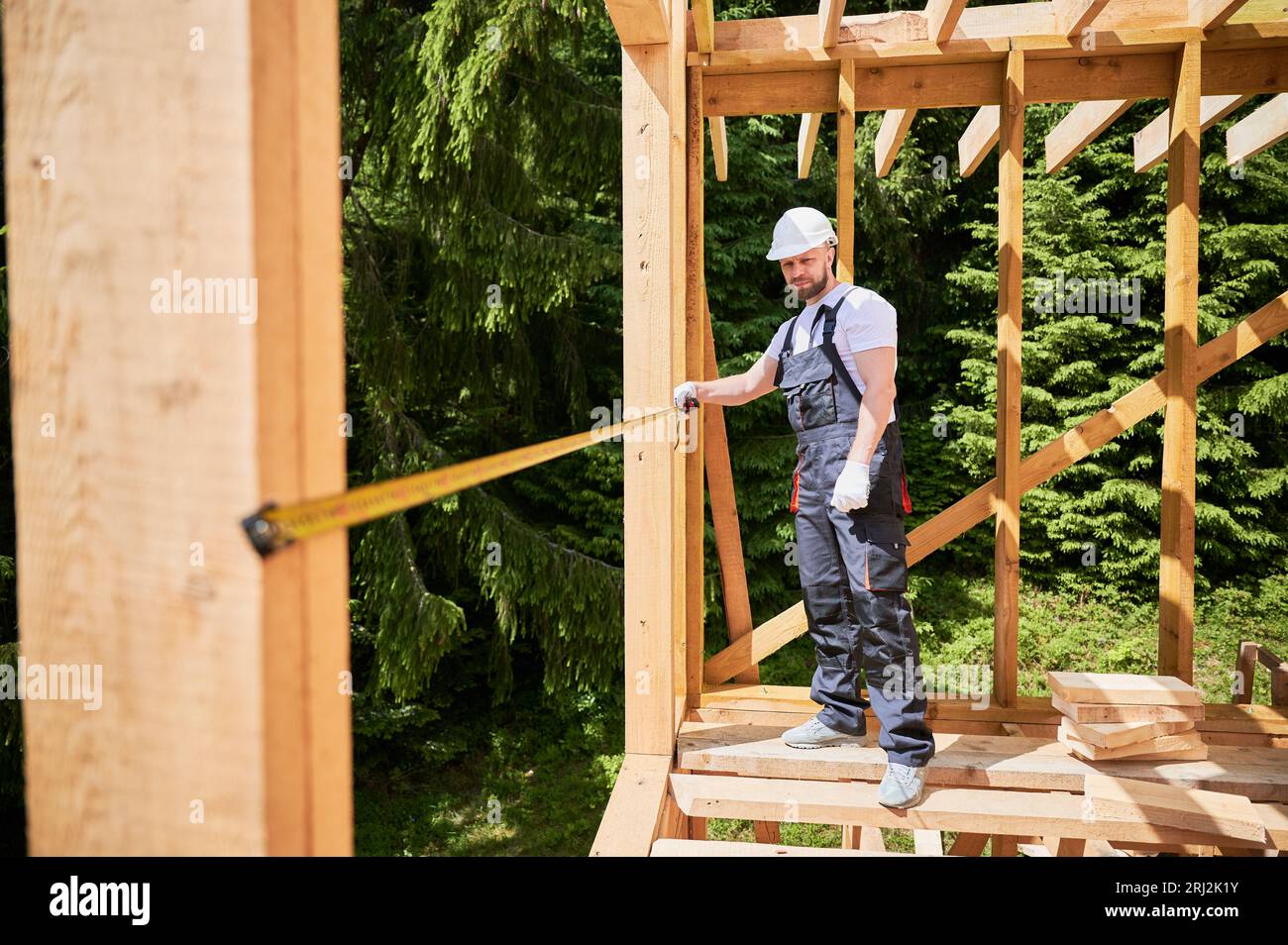 Carpenter constructing wooden skeleton building. Man measures distances ...