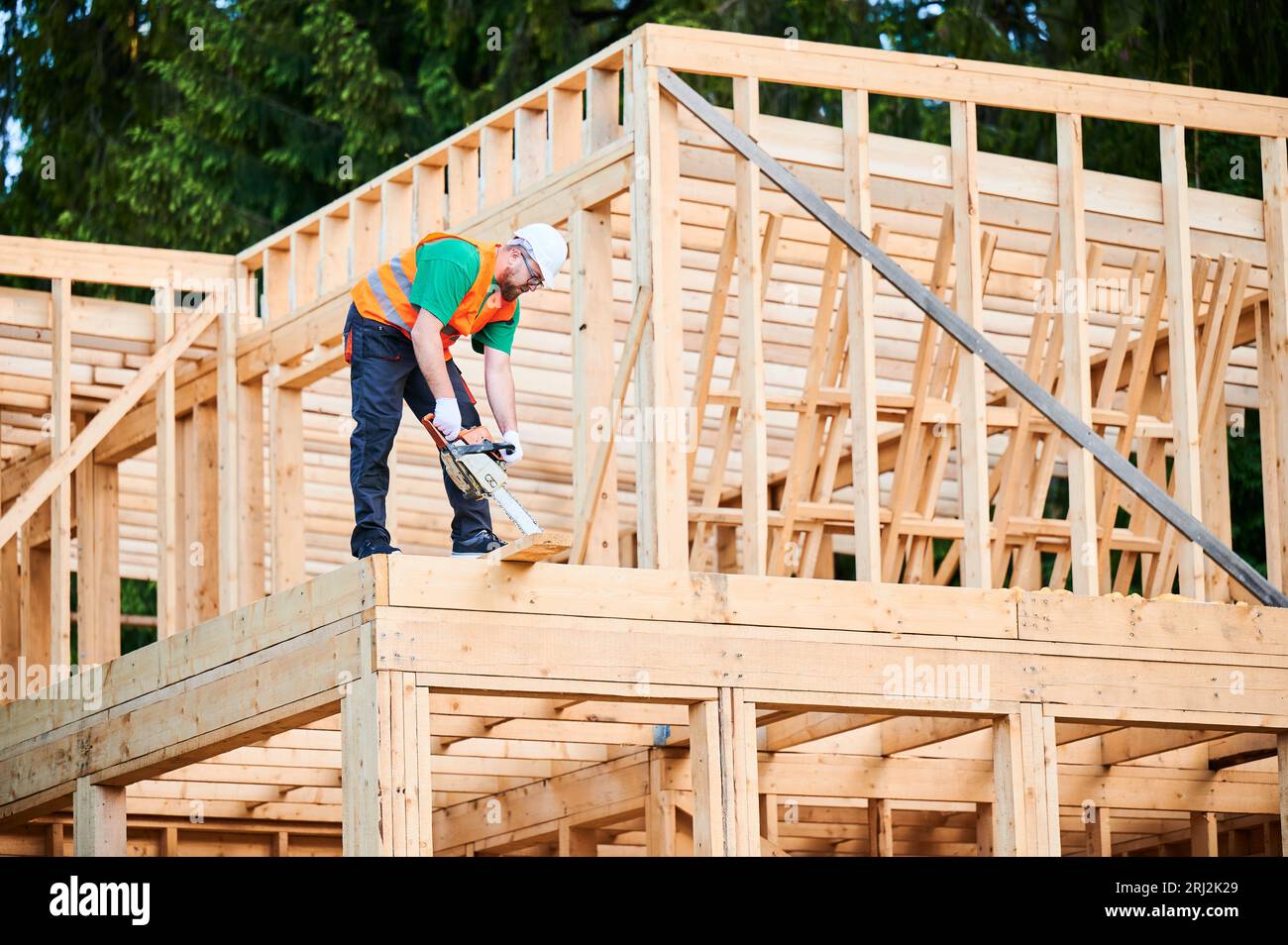 Carpenter using chainsaw for cutting wooden plank. Man worker building ...