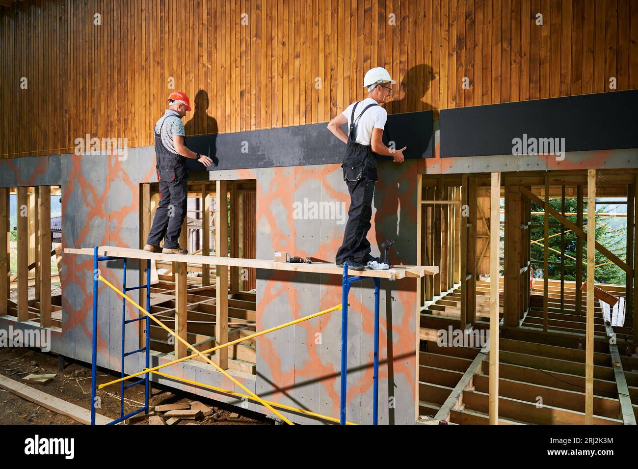 Carpenters constructing wooden framed house. Two men workers cladding ...