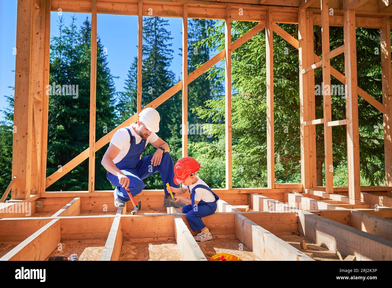 Father with toddler son building wooden frame house. Male worker ...