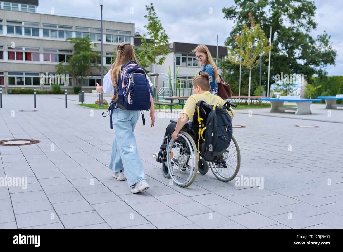 Children going to school, boy in wheelchair and girls, rear view Stock ...