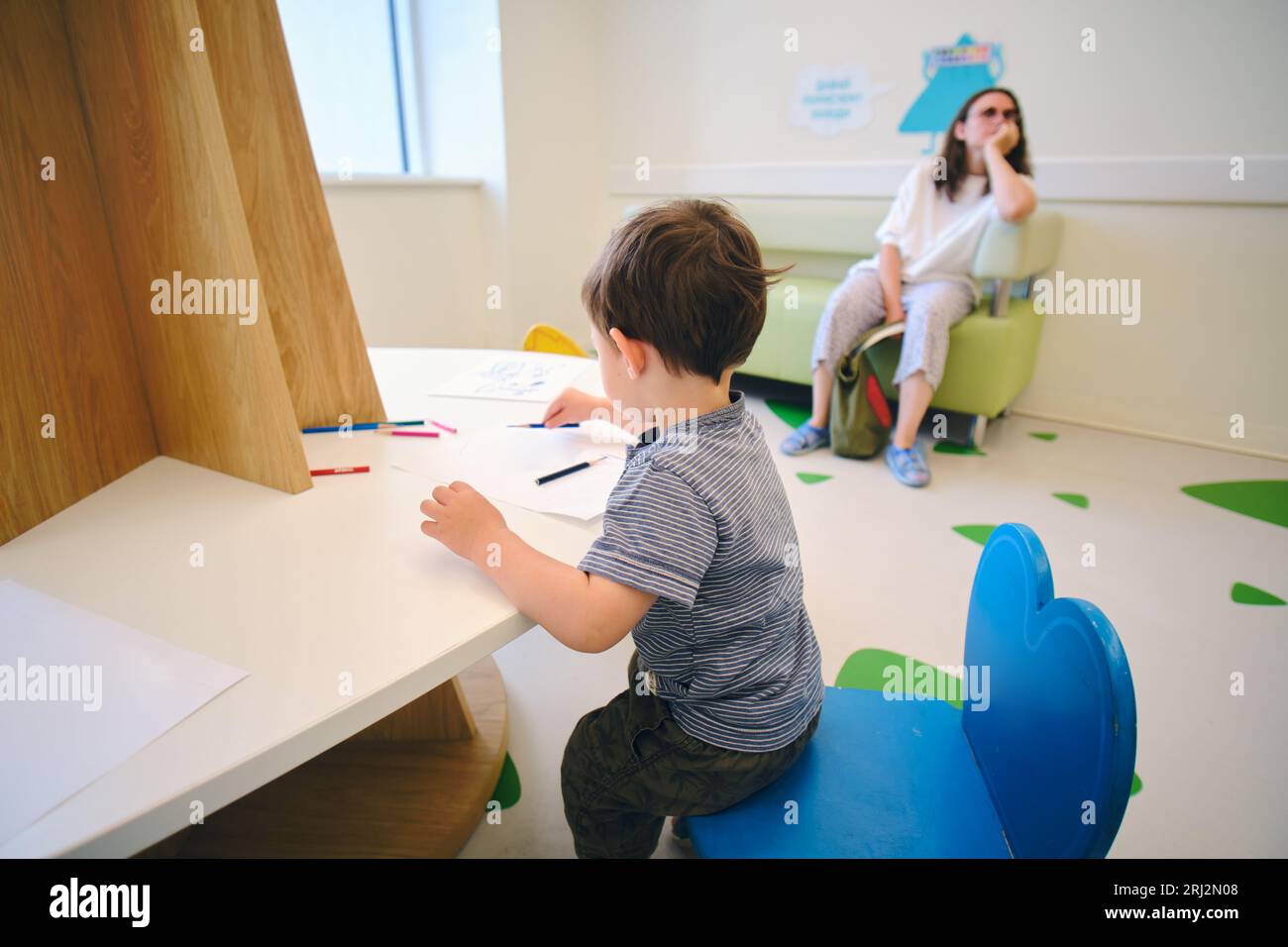 The child with her mother is patiently sitting in the hall of the ...