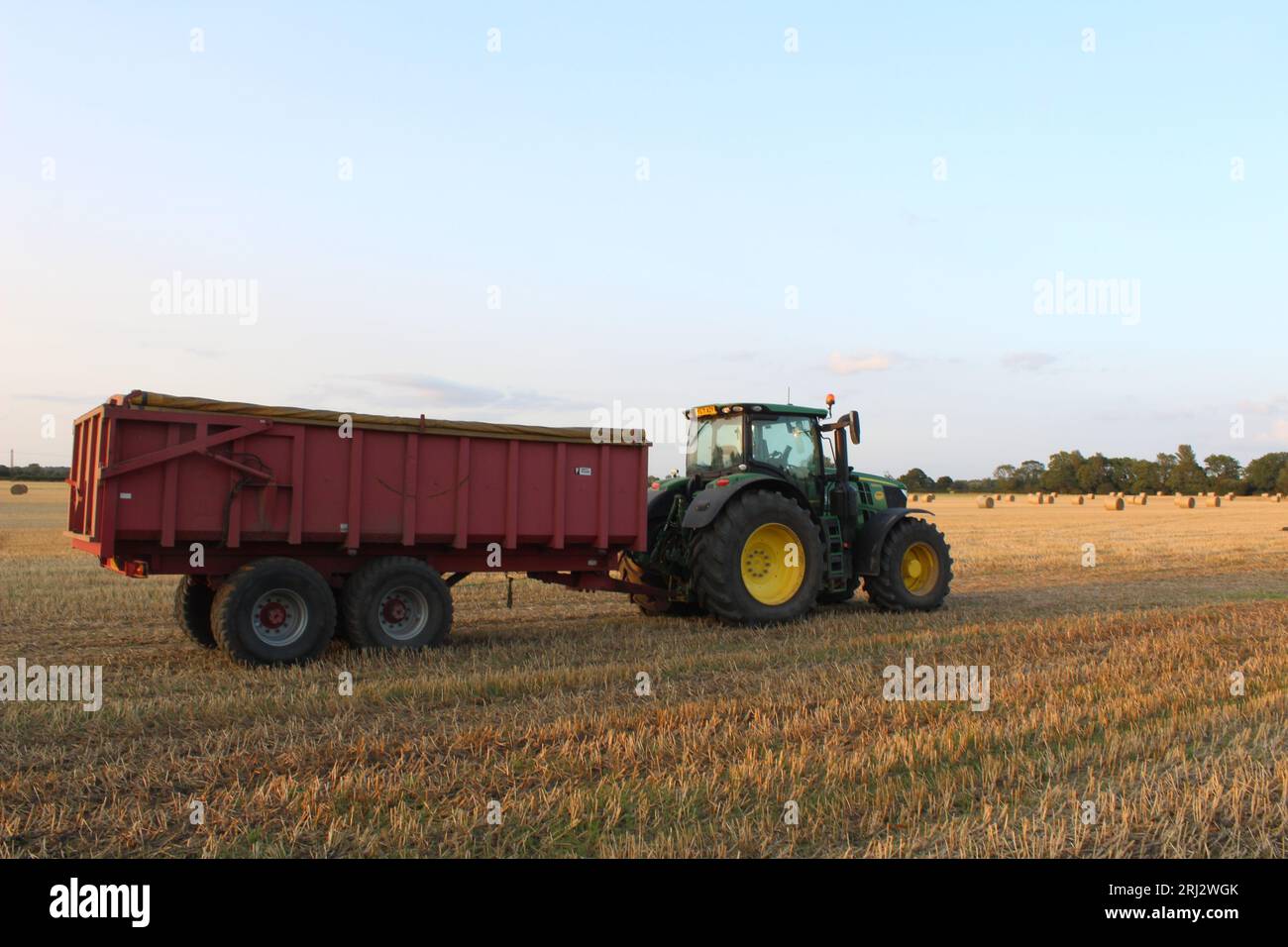 Tractor and trailer working on farm land on a summers evening Near ...