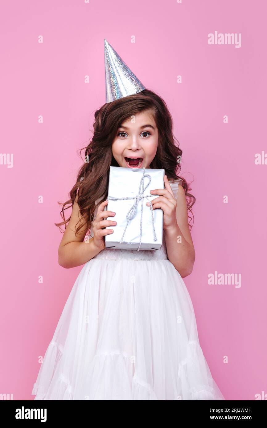 Portrait of surprised kid girl n birthday party princess hat holding ...
