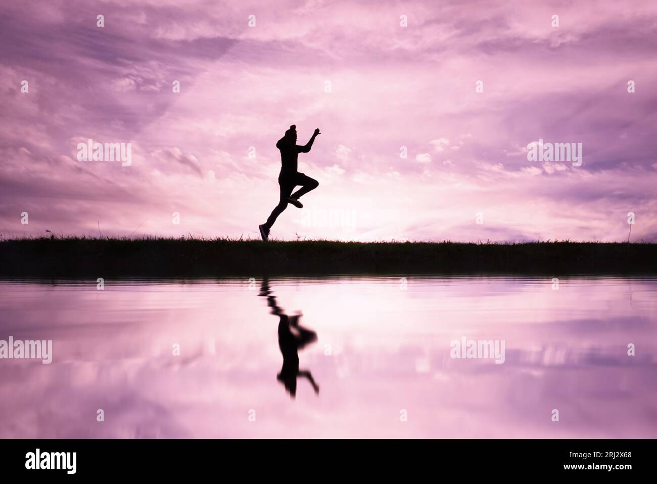 man jumping over a pond with a sunset background Stock Photo - Alamy