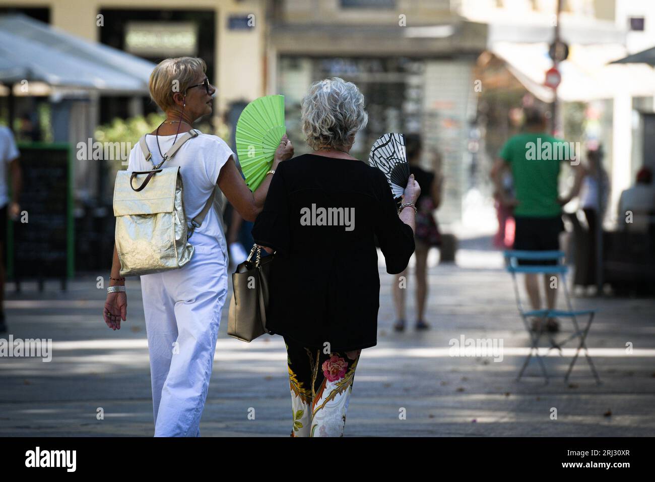 Two people fan themselves to cool off during a heatwave. Météo-France ...