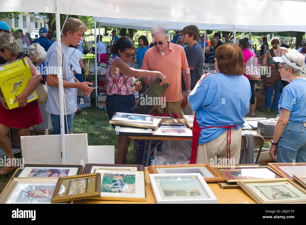 A group of shoppers examining the goods at an annual church fair and ...