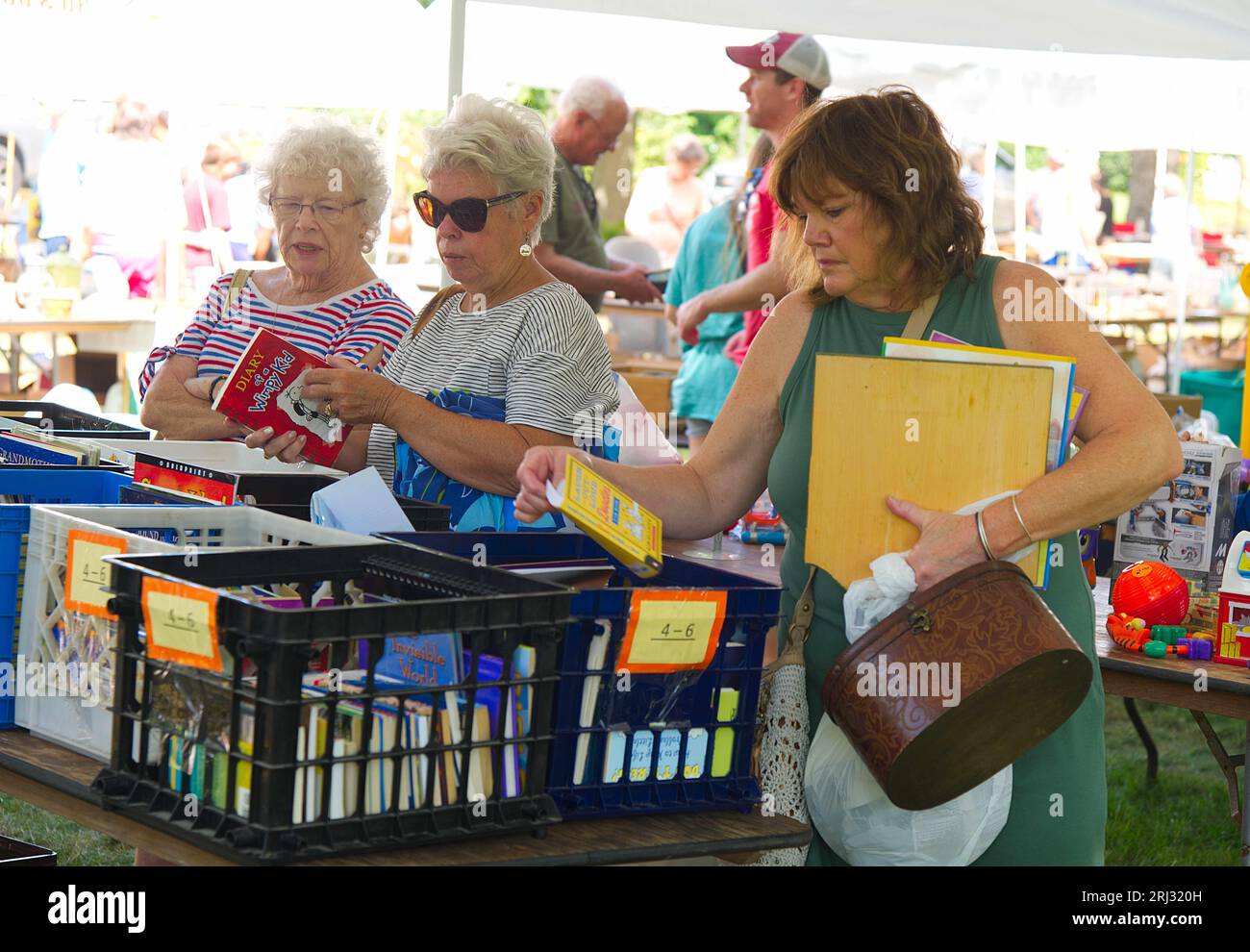 Women examining books at an annual church fair and flea market, Dennis ...