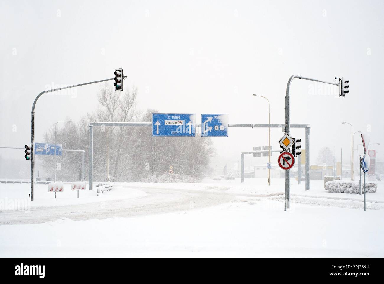 Empty winter road with traffic signs in snow storm with traffic lights ...