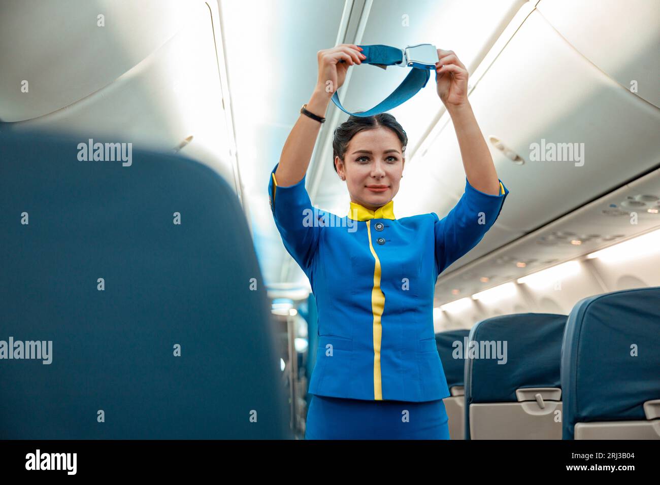 Woman stewardess demonstrating how to use safety belt in aircraft Stock ...