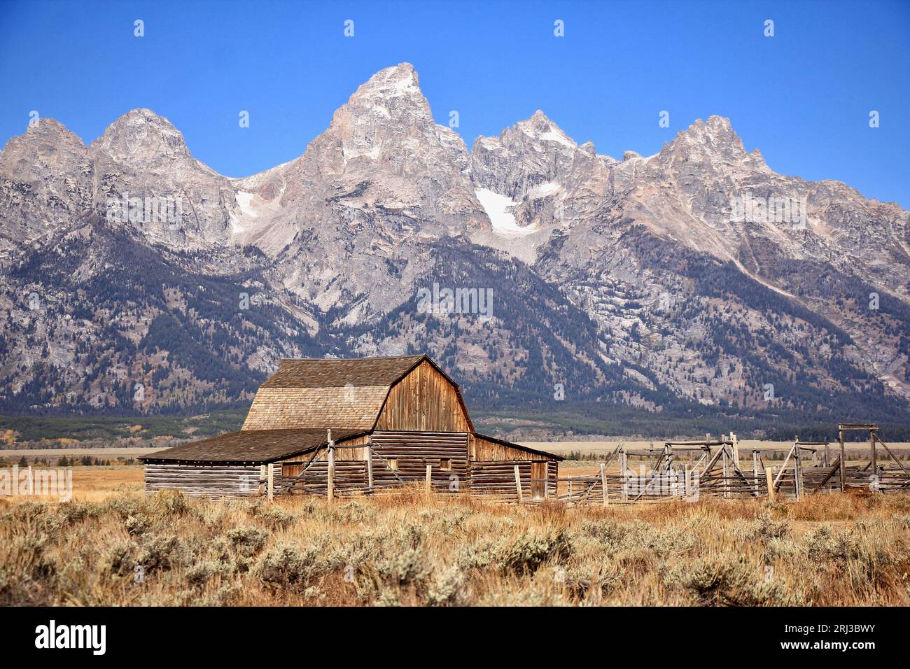 A rustic old barn in a lush green meadow, with a scenic mountain ...