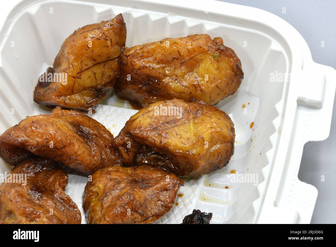 A fresh batch of fried plantains in a white plastic container Stock ...