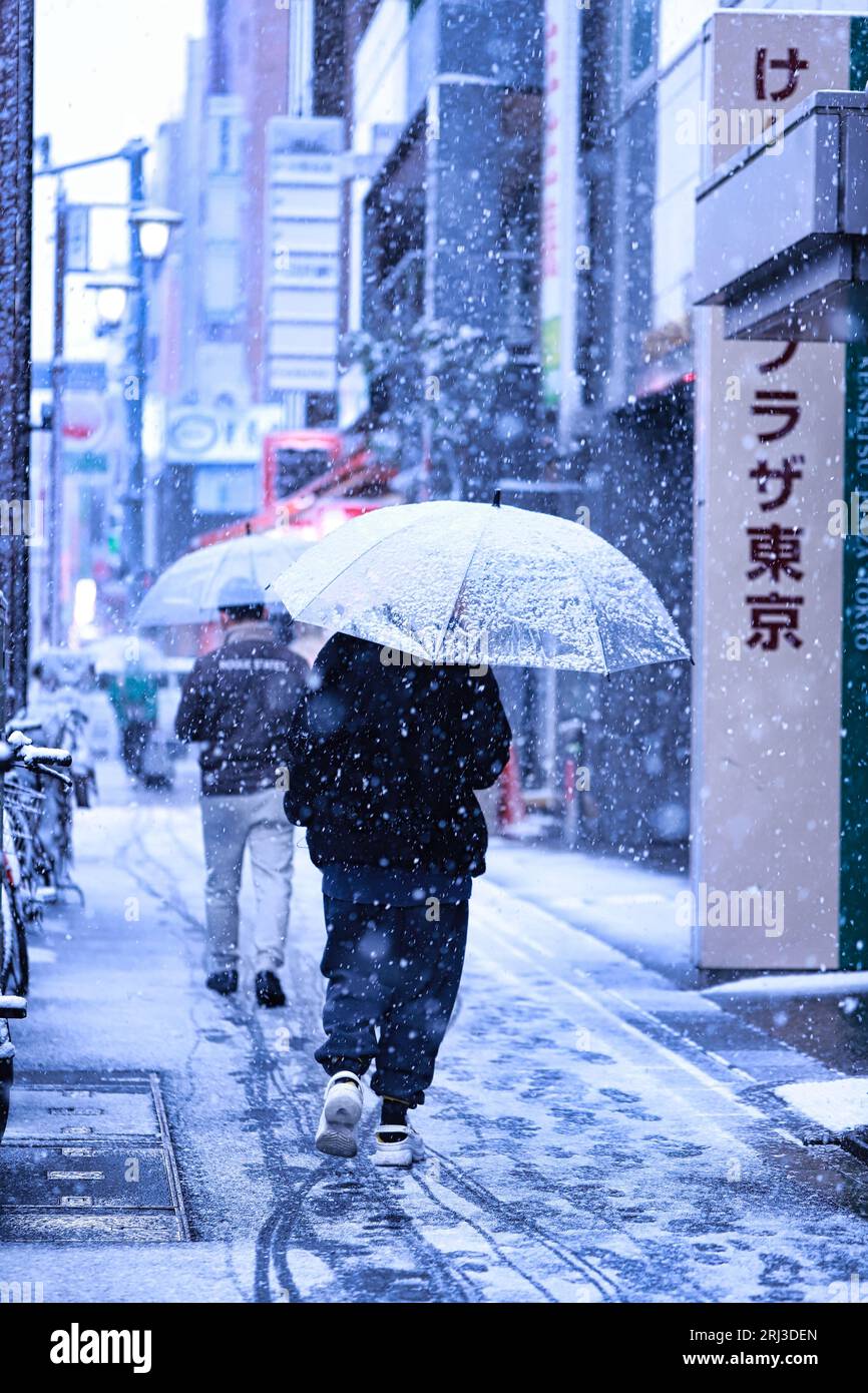 Two people walk along a street in Tokyo's Shinjuku district during a ...